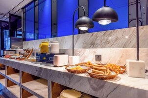 Um buffet de café da manhã com diversos alimentos e uma máquina de café.