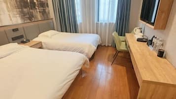 Quarto de hotel com duas camas, uma escrivaninha de madeira, uma cadeira, televisão e uma janela com cortinas.