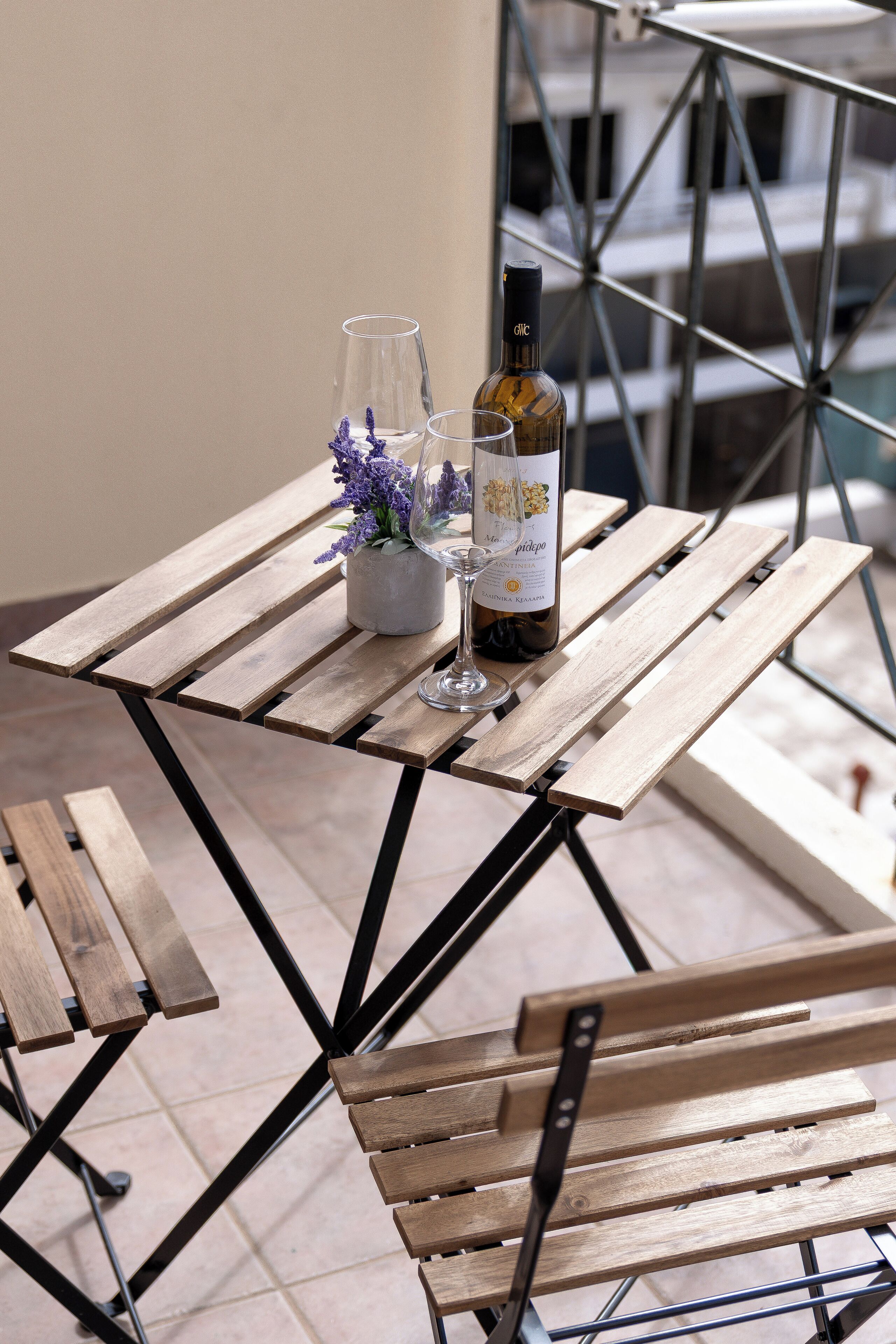 Uma mesa de madeira com uma garrafa de vinho e um copo, ao lado de um corrimão de metal.