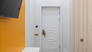 Um corredor estreito com uma porta branca, uma parede amarela de um lado e uma parede branca do outro.