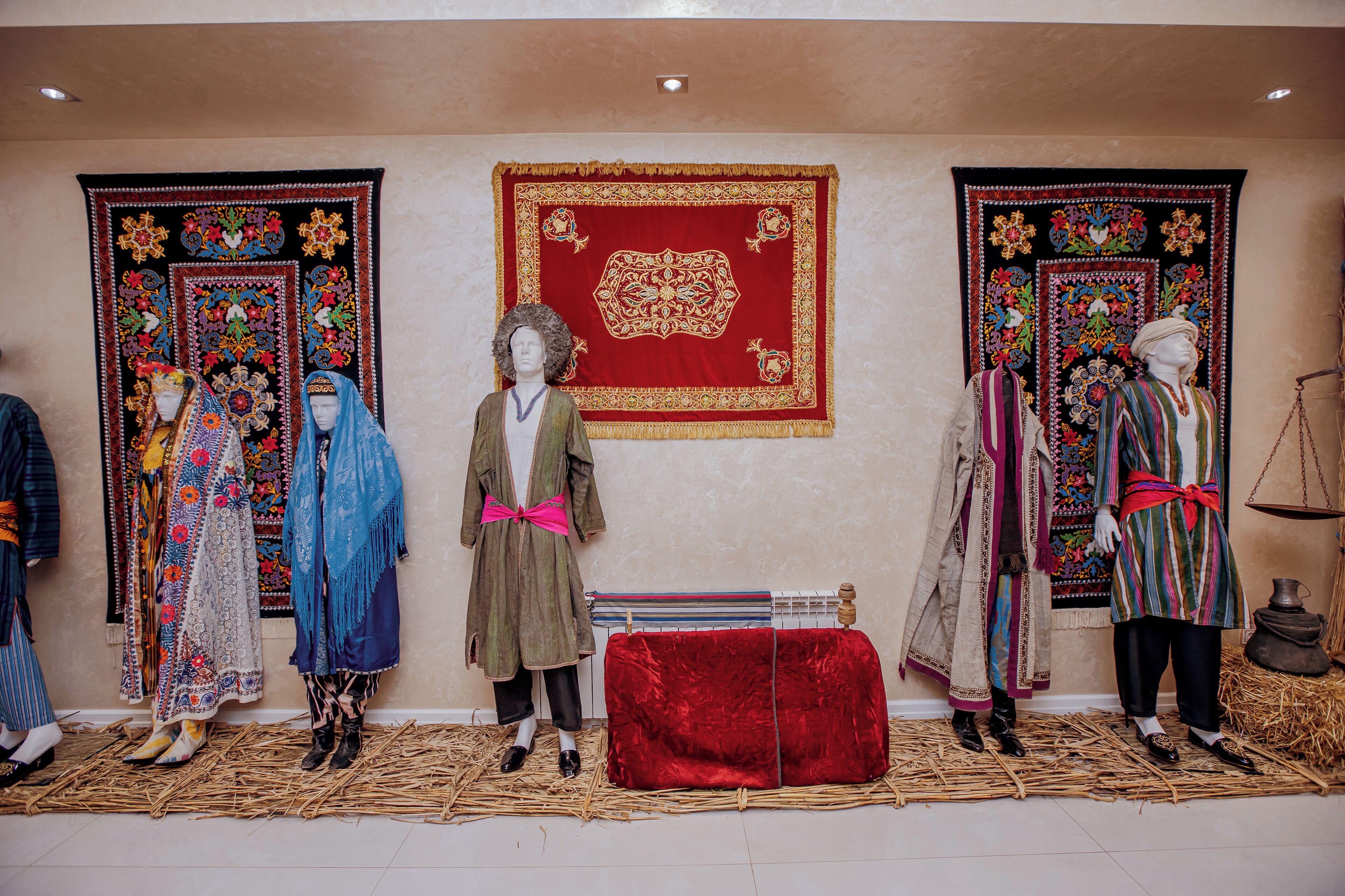 Mannequins vestidos com trajes típicos, um tapete vermelho e uma balança.