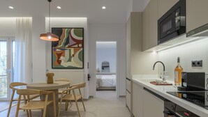 Cozinha moderna com área de refeições, micro-ondas, máquina de café e um quadro na parede.
