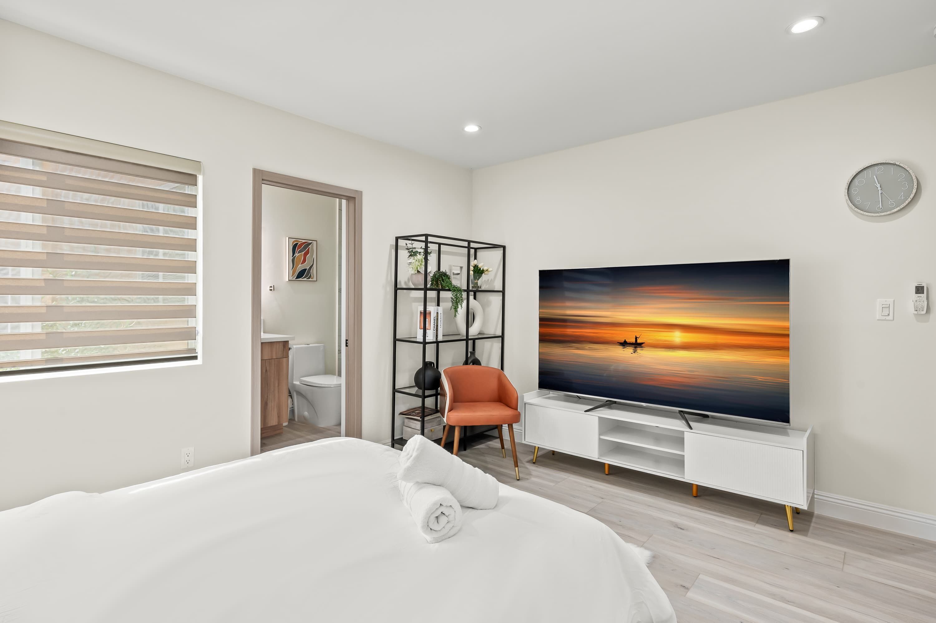 Quarto moderno com uma cama grande, uma televisão e uma estante de livros.