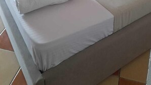 Quarto de hotel com uma cama grande, uma cama beliche menor, uma mesa de cabeceira e um criado-mudo.