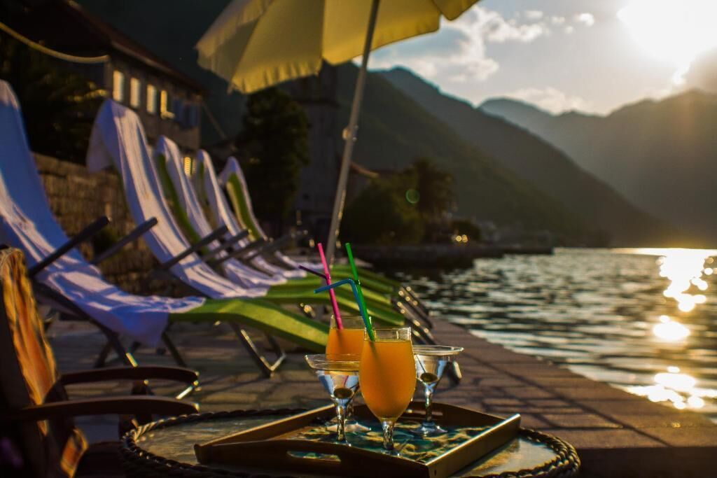 Ambiente de piscina com espreguiçadeiras e uma mesa com bebidas.