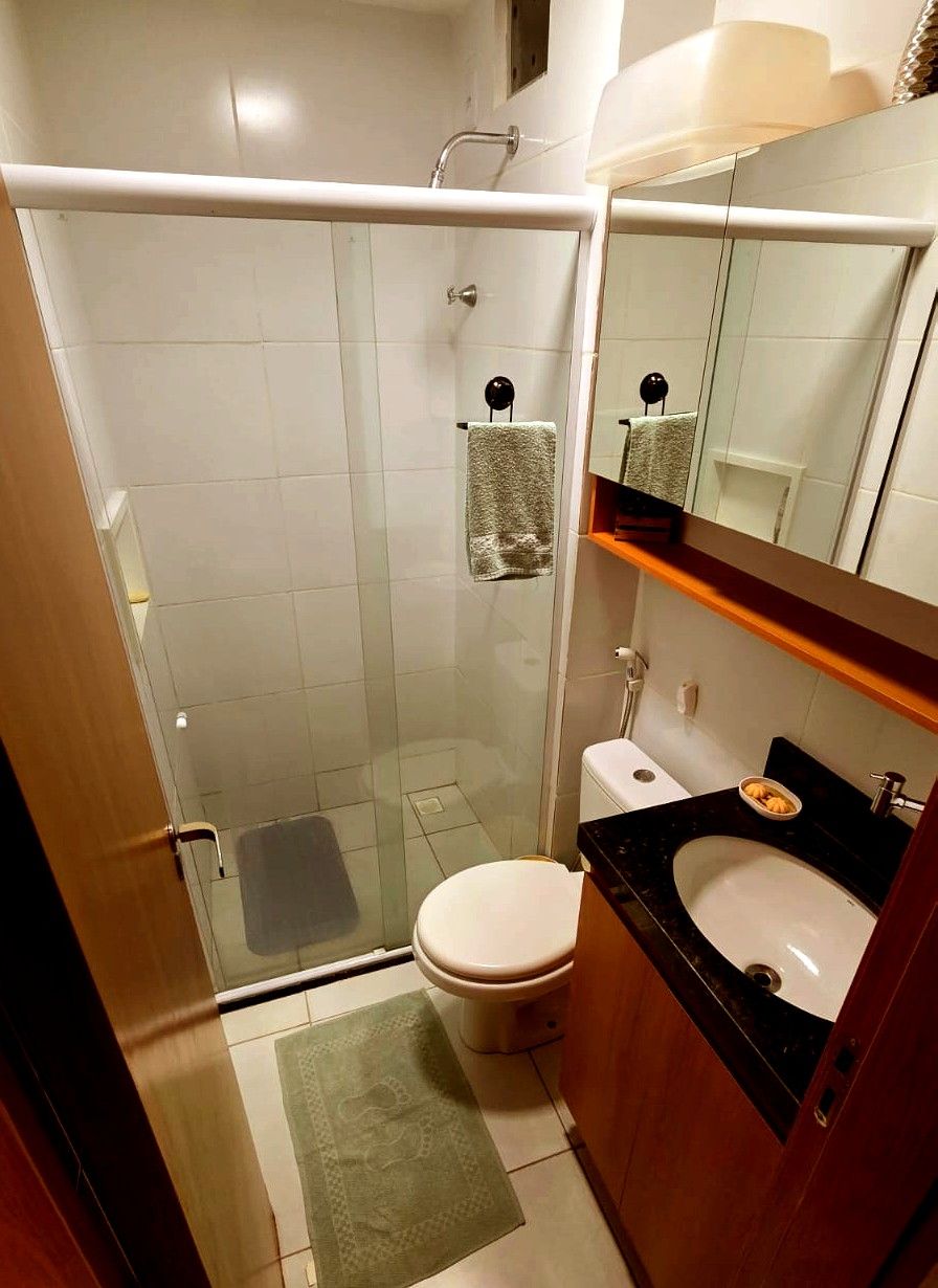 Uma casa de banho com cabine de duche em vidro, sanita, lavatório e espelho.