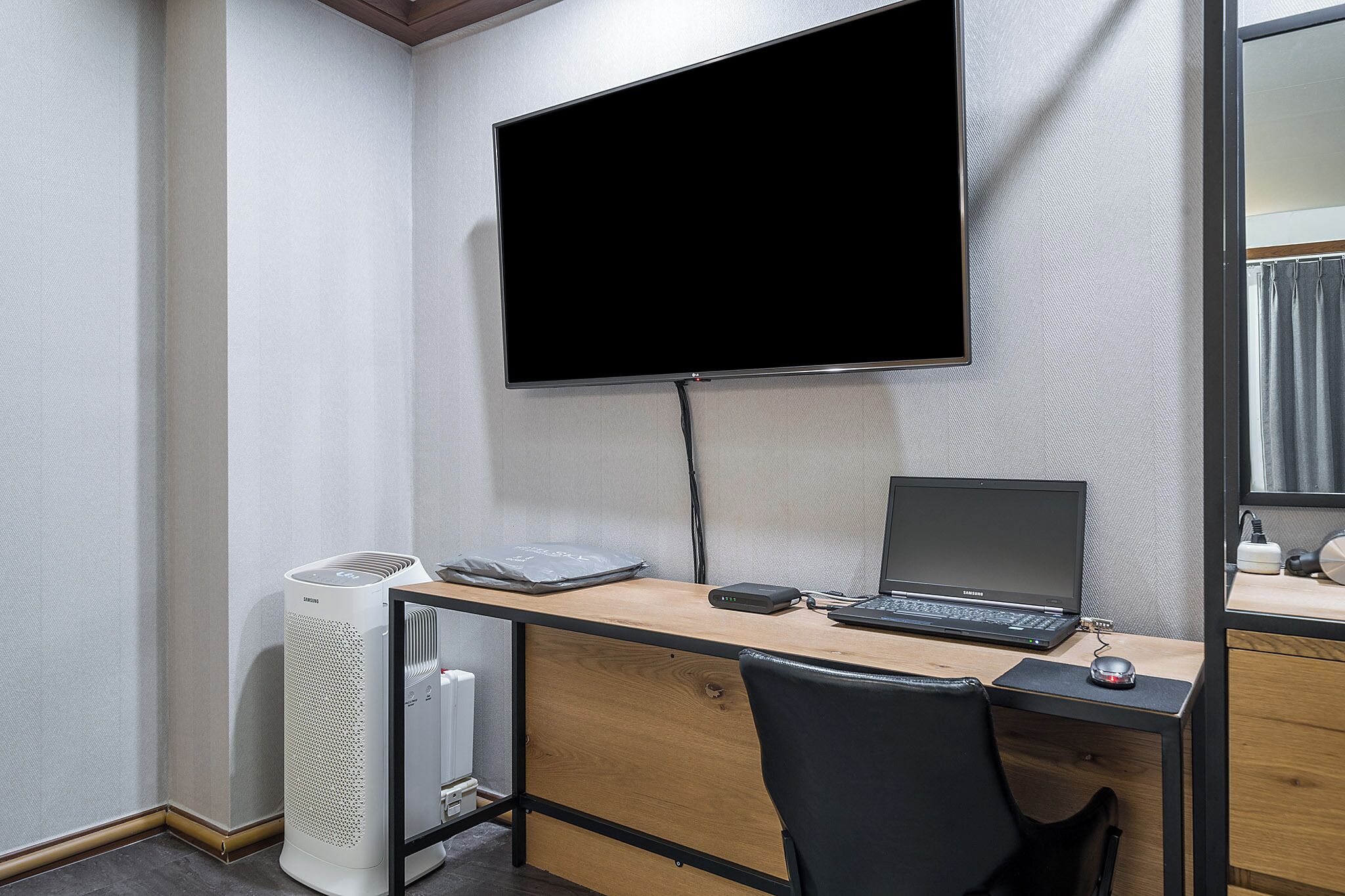 Um espaço de escritório moderno com uma televisão de tela grande, um computador de mesa e um aquecedor vertical.