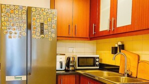 Uma cozinha com armários de madeira, eletrodomésticos de aço inoxidável e três tigelas de comida na bancada.