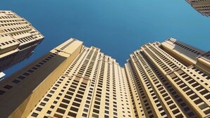 Vista de edifícios altos e amarelos com várias janelas e varandas, sob um céu azul claro.