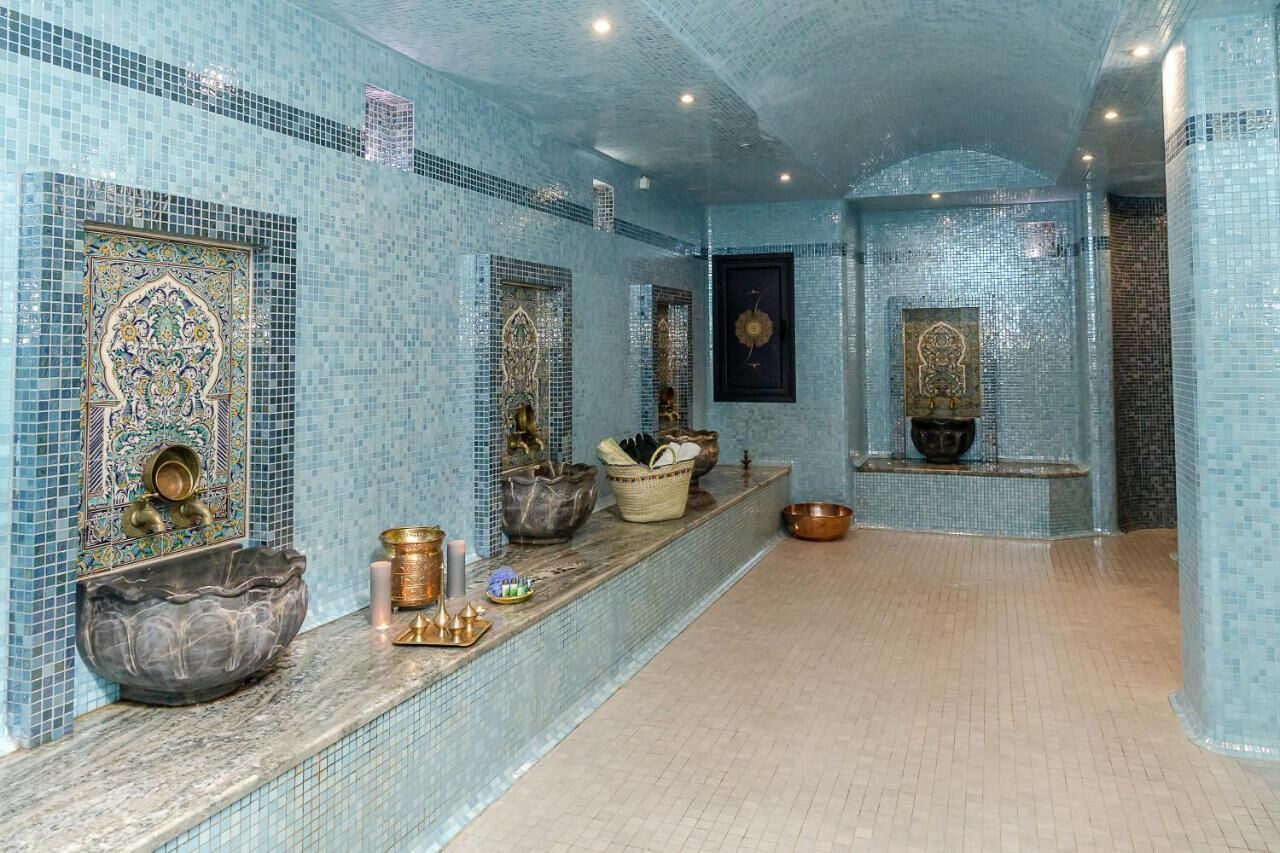 Um quarto com chão e paredes azulejadas, um balcão comprido com objetos decorativos e uma parede estampada.