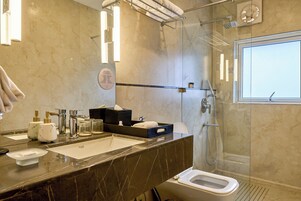 Um banheiro moderno com pia de mármore, chuveiro com box de vidro e vaso sanitário.