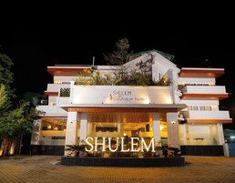 Um hotel moderno chamado Shulem Boutique Hotel, com entrada imponente e área de estar ao ar livre.