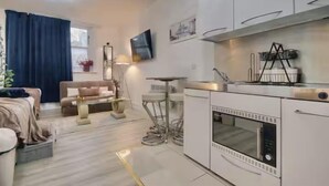 Uma cozinha moderna com armários brancos, forno embutido e área de refeições com mesa e cadeiras.
