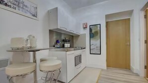 Uma cozinha compacta com uma ilha central, dois banquetes, uma cafeteira e um micro-ondas.