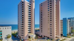 Um hotel moderno com vários andares, entrada coberta e vista para a praia.