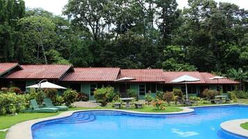 Um hotel com piscina, espreguiçadeiras verdes e guarda-sóis.
