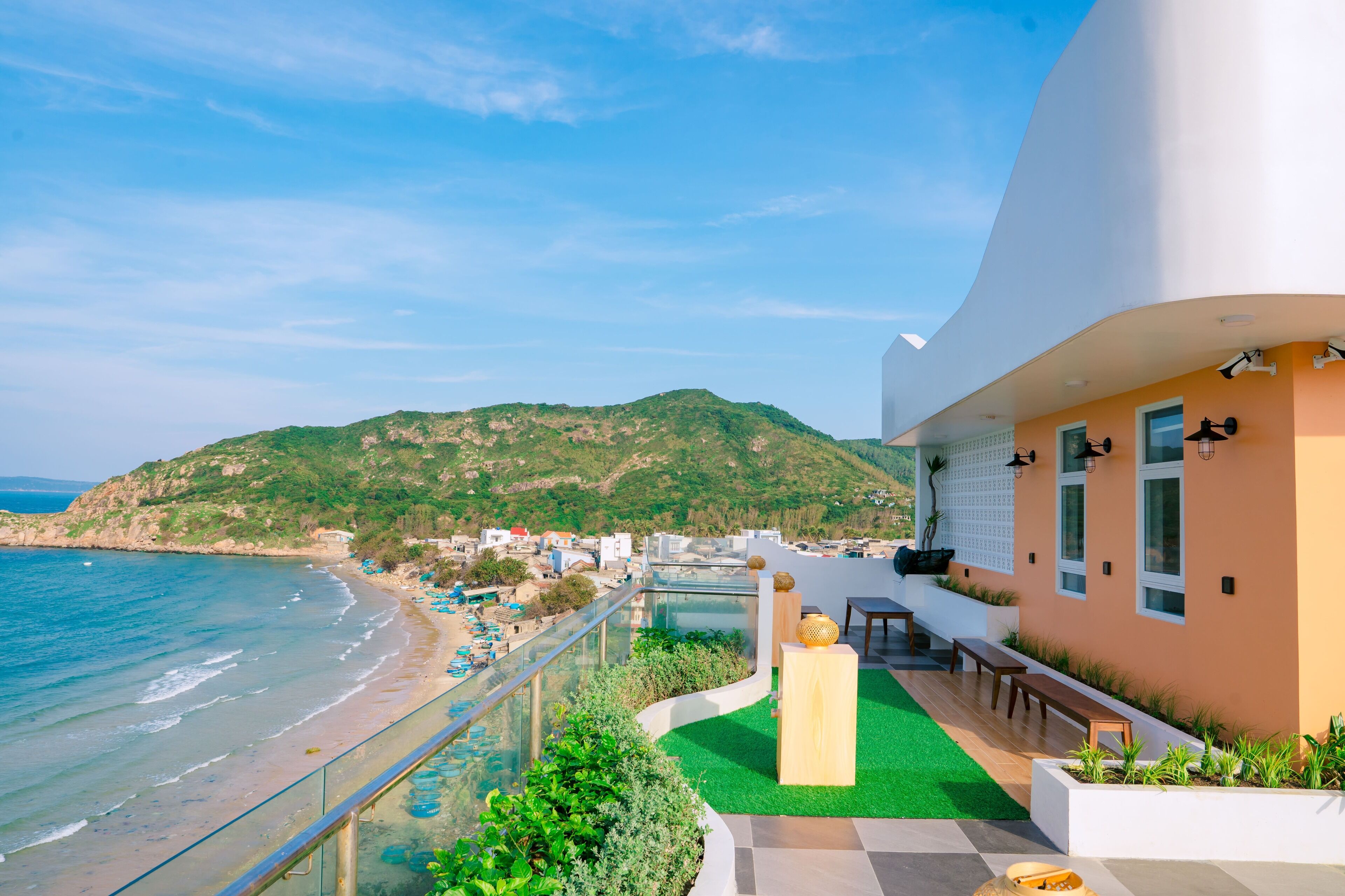 Um edifício moderno com varanda com vista para uma praia e uma montanha.