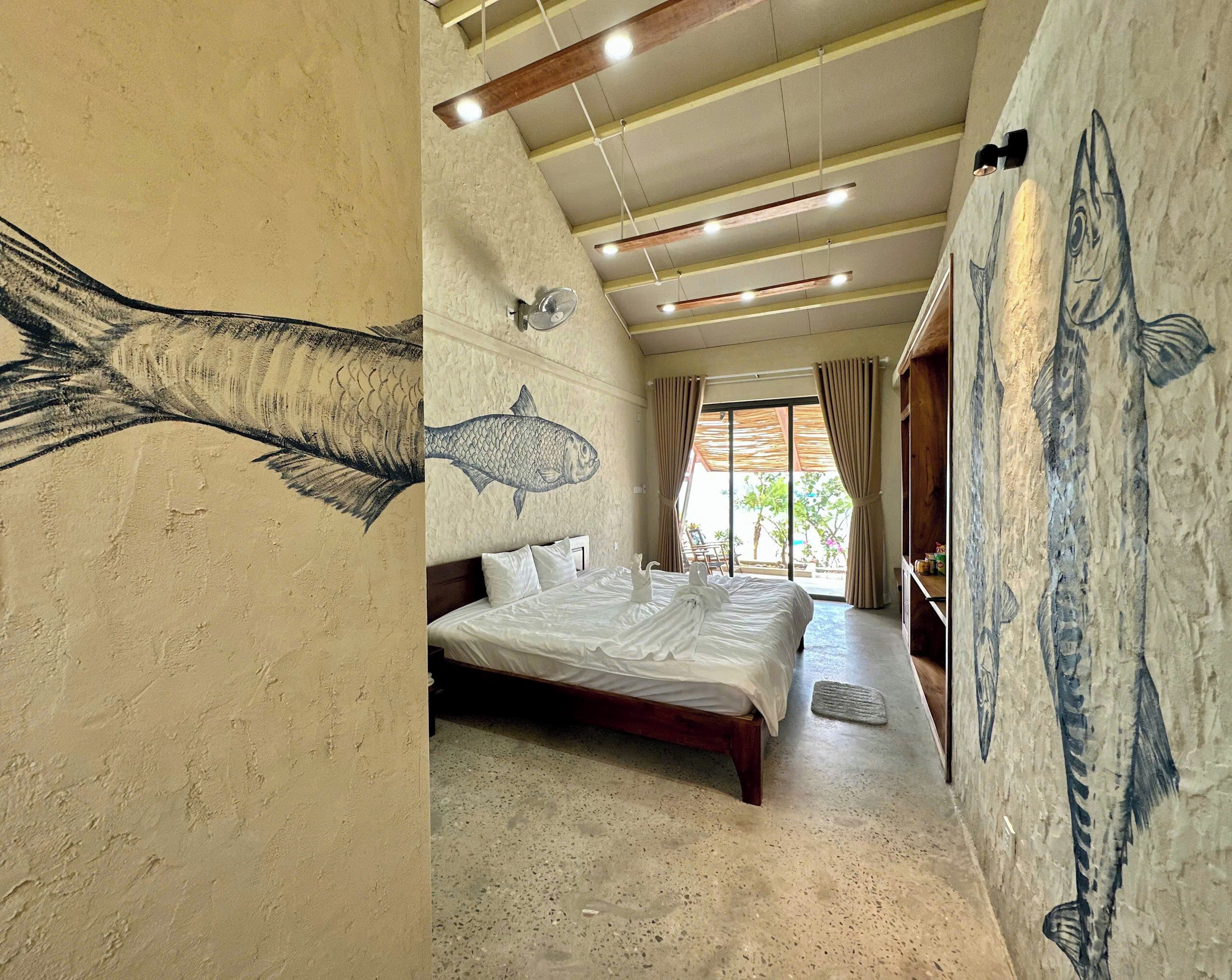 Quarto com cama, ventilador de teto e paredes com mural de peixes.