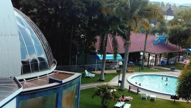 Uma área de piscina com uma piscina grande, espreguiçadeiras e um pavilhão coberto.