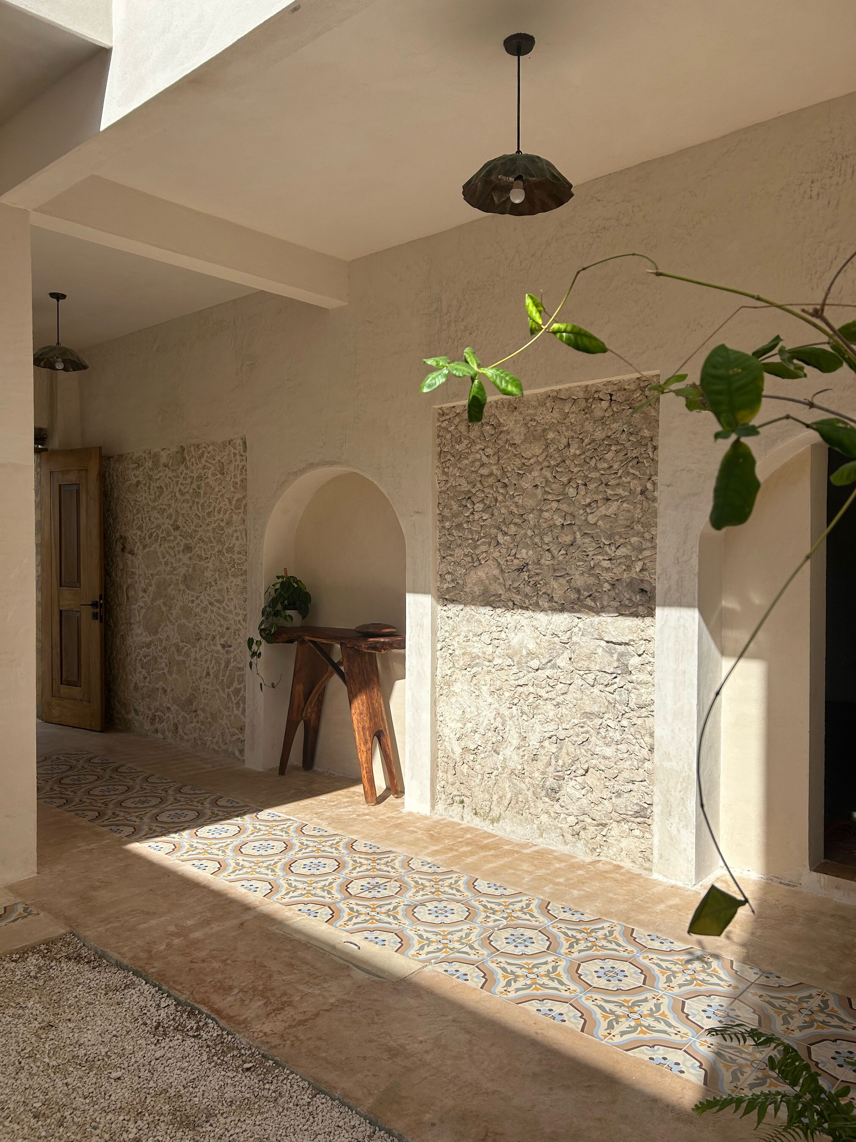 Um interior amplo com soalho em azulejos, um banco de madeira e uma parede de pedra.