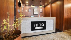 Uma área de recepção de hotel com interior em madeira, balcão de atendimento e quadros nas paredes.
