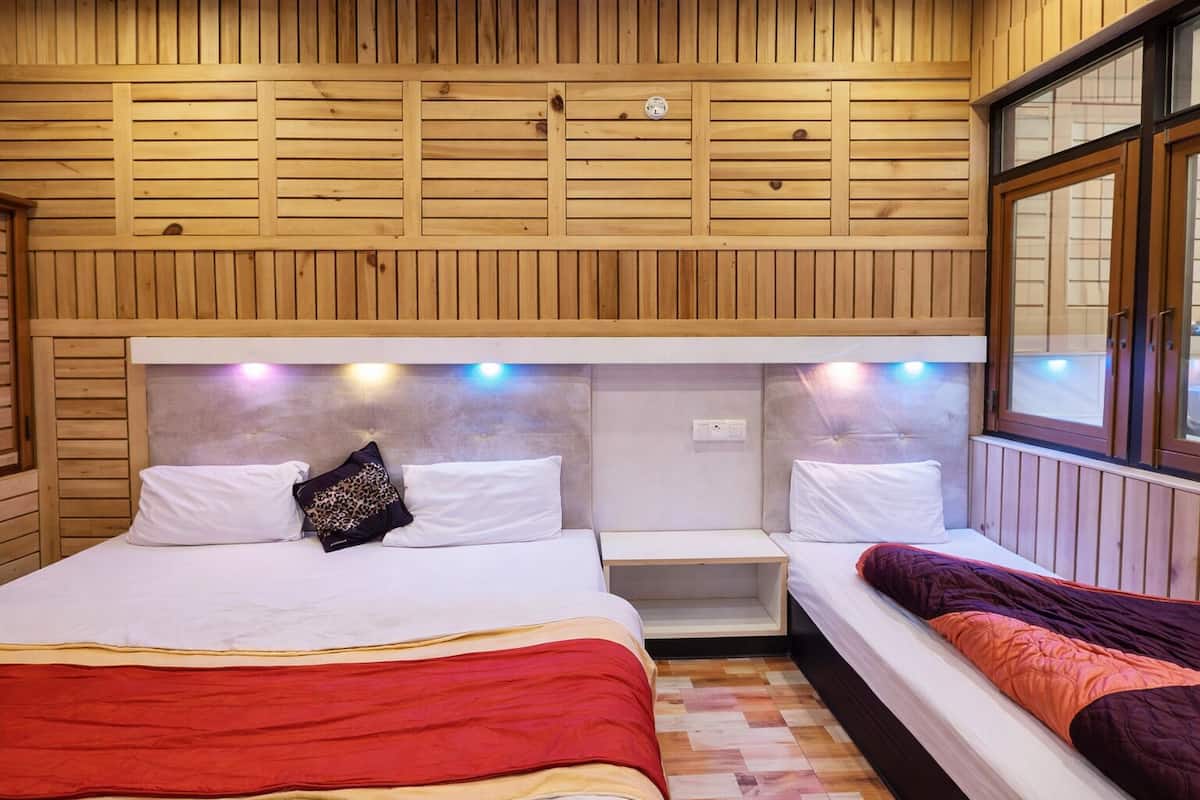 Quarto com duas camas, uma mesinha e uma janela.