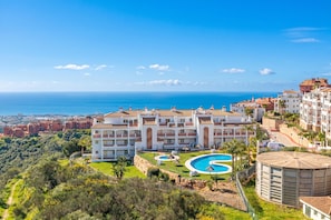 Um hotel com vários andares, piscina e vista para o mar.