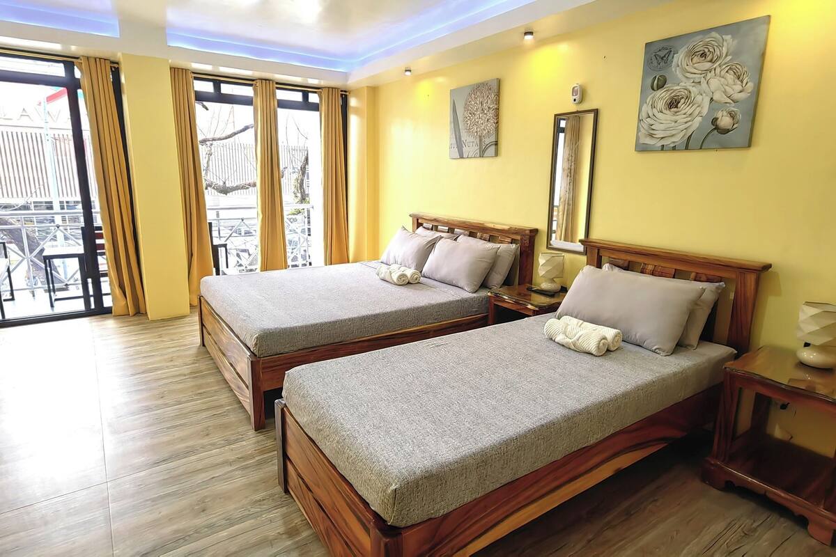 Quarto de hotel com duas camas, varanda e obras de arte nas paredes.