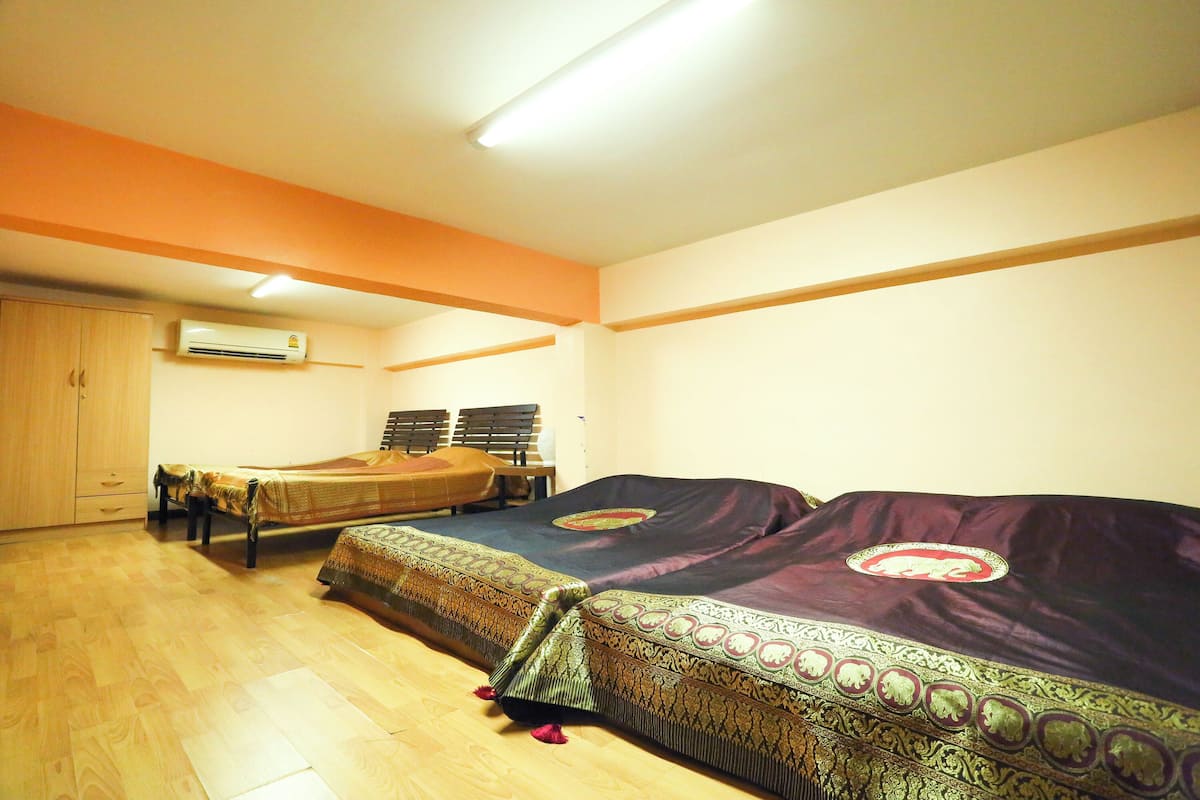 Quarto com duas camas, piso de madeira, ar condicionado e um guarda-roupa.