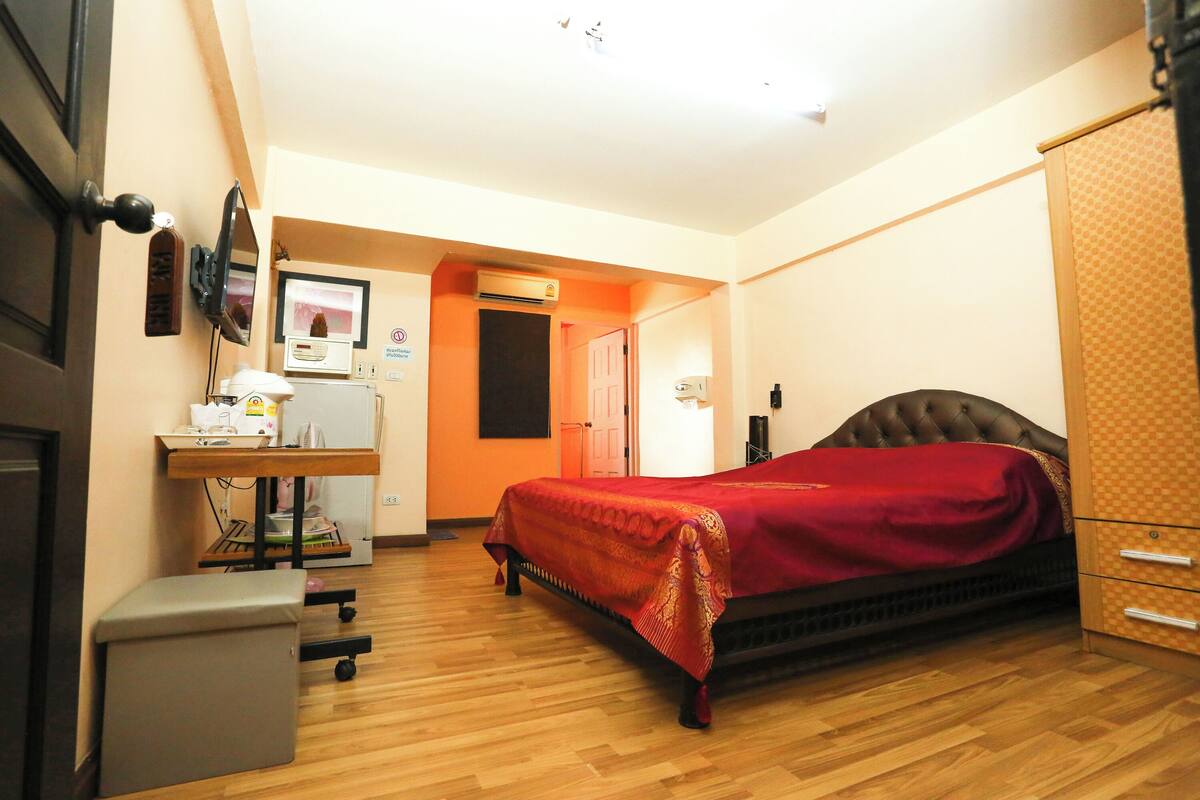 Quarto com cama, escrivaninha, guarda-roupa e porta que dá para outro cômodo.