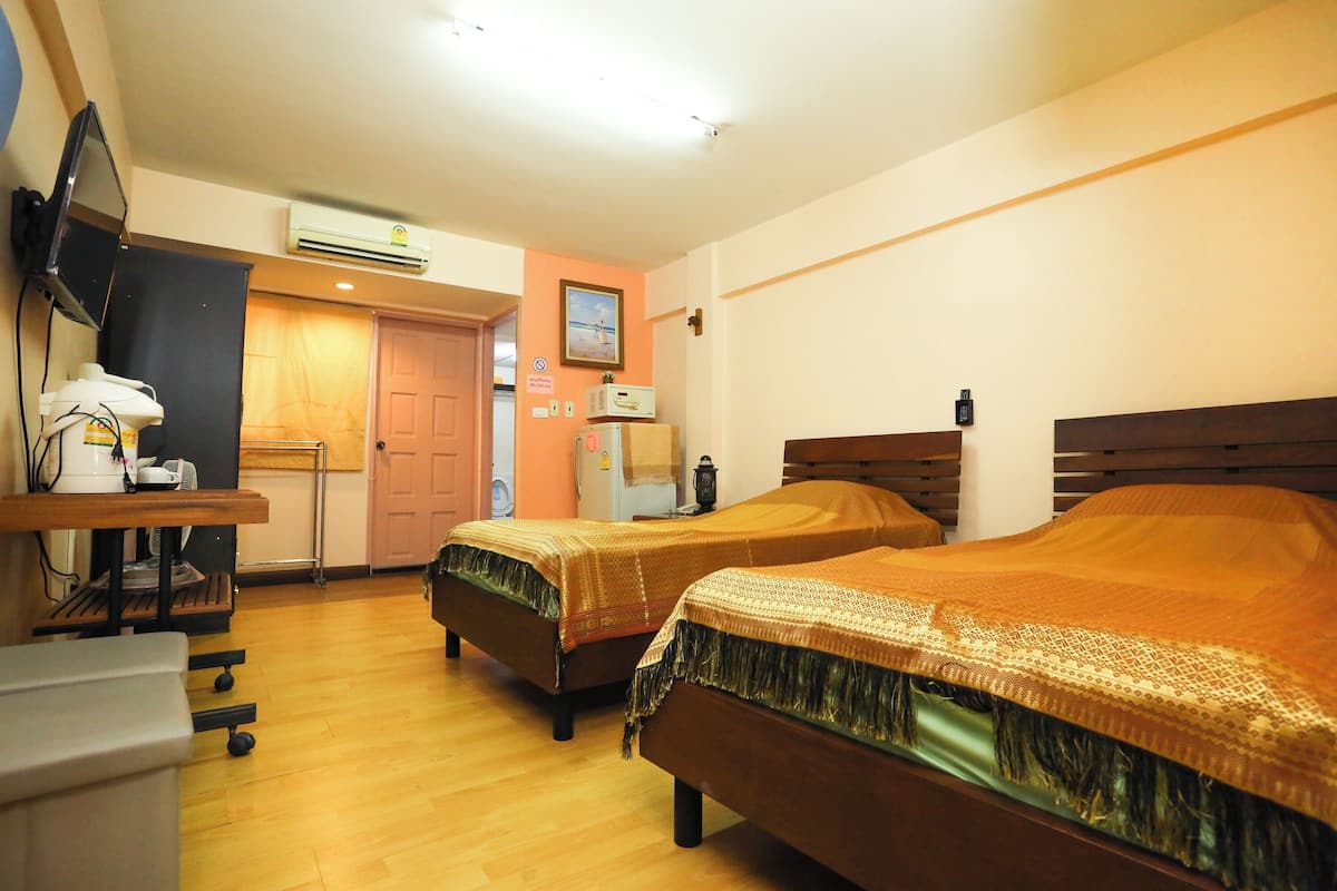 Quarto de hotel com duas camas, uma mesa de escritório com computador, ar condicionado e porta que dá para outro quarto.