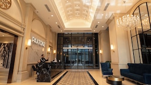 Um saguão com um lustre imponente, um balcão de recepção e uma entrada para o West Court.