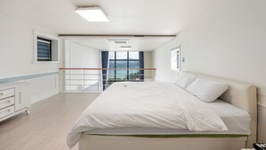 Quarto de hotel com cama, escrivaninha, janela com vista e varanda.