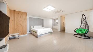 Quarto moderno com cama, cadeira suspensa e kitchenette.