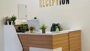 Uma receção com design moderno, com acabamento em madeira e balcão branco. Acima do balcão, existem relógios a indicar as horas de Londres, EUA e Dubai.