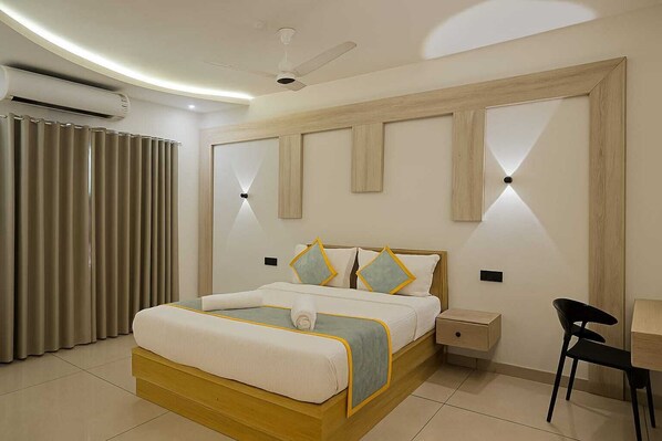 Quarto moderno com cama, mesas de cabeceira, escrivaninha e uma cadeira.