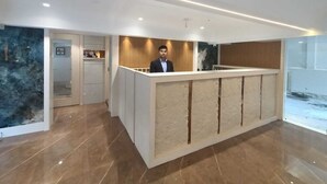 Uma área de recepção com design moderno, destacando-se um balcão de atendimento, uma parede de destaque em madeira e uma grande janela com vista para o exterior.