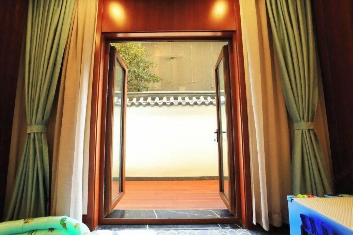 Quarto com porta de vidro deslizante que dá para uma varanda, piso de madeira e chão ladrilhado.