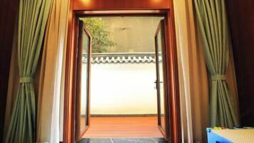 Quarto com porta de vidro deslizante que dá para uma varanda, piso de madeira e chão ladrilhado.
