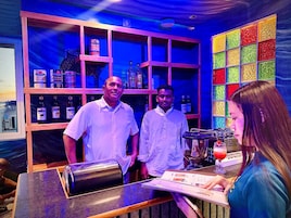 Uma área de bar com prateleiras de garrafas, um balcão com menu e uma parede colorida.