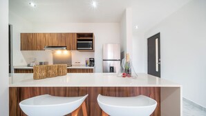 Cozinha moderna com armários de madeira, geladeira de aço inoxidável e bancada branca.