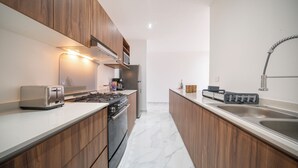 Cozinha moderna com armários de madeira, uma pia de aço inoxidável e um forno embutido.