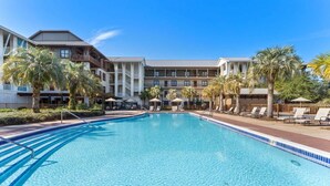Um hotel com uma grande piscina, palmeiras e áreas de estar ao ar livre.