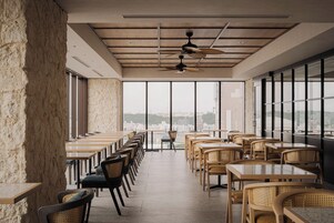 Um restaurante com mesas e cadeiras altas, janelas amplas e vista para a cidade.