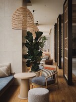 Um interior moderno com uma mesa redonda, uma planta grande e uma luminária suspensa de vime.