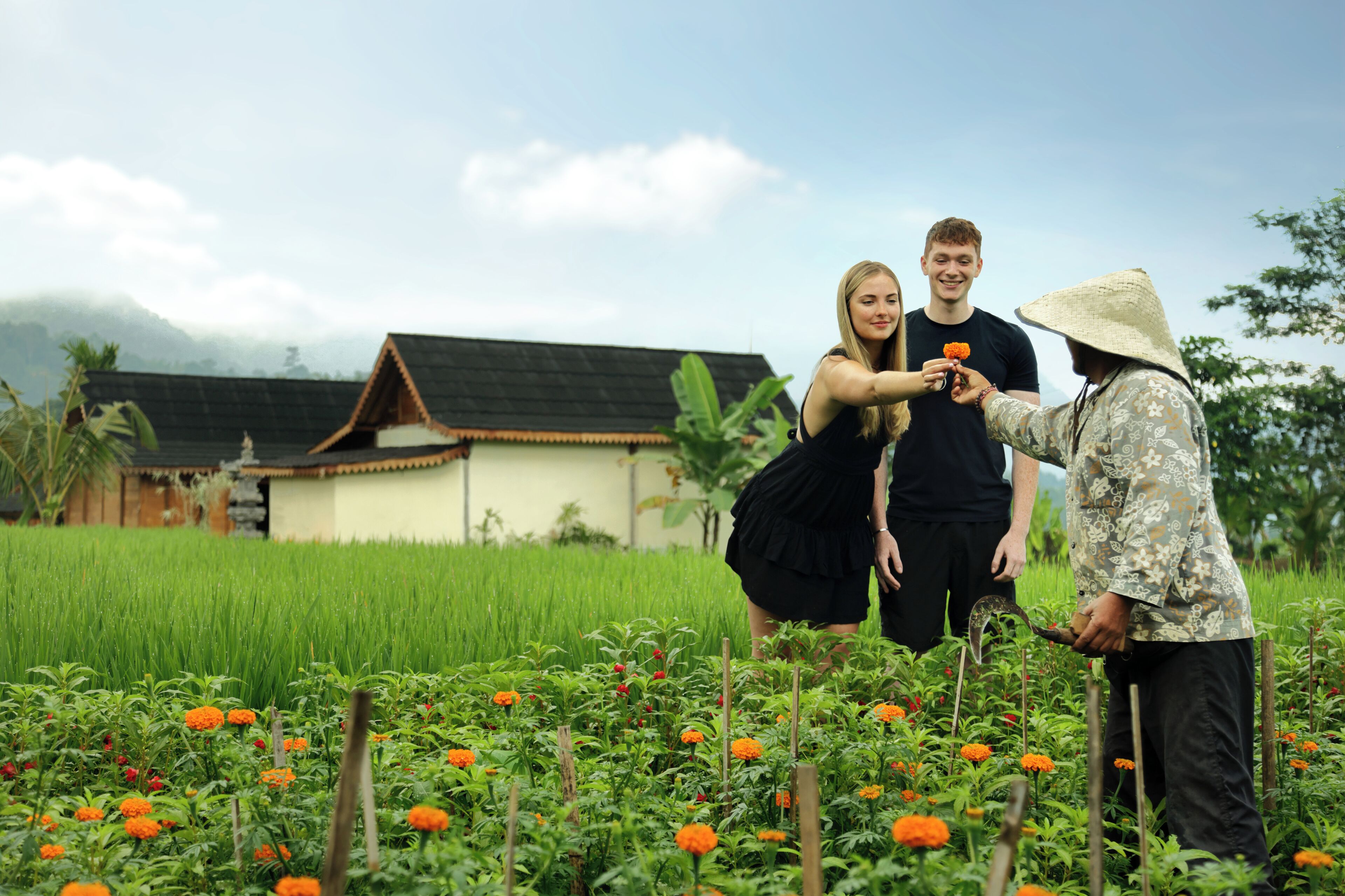 Paisagem rural com uma casa, um campo de plantações e uma pessoa vestida com traje típico.