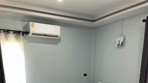 Quarto de hotel com cama, mesa de cabeceira, ar condicionado e quadro pendurado na parede.