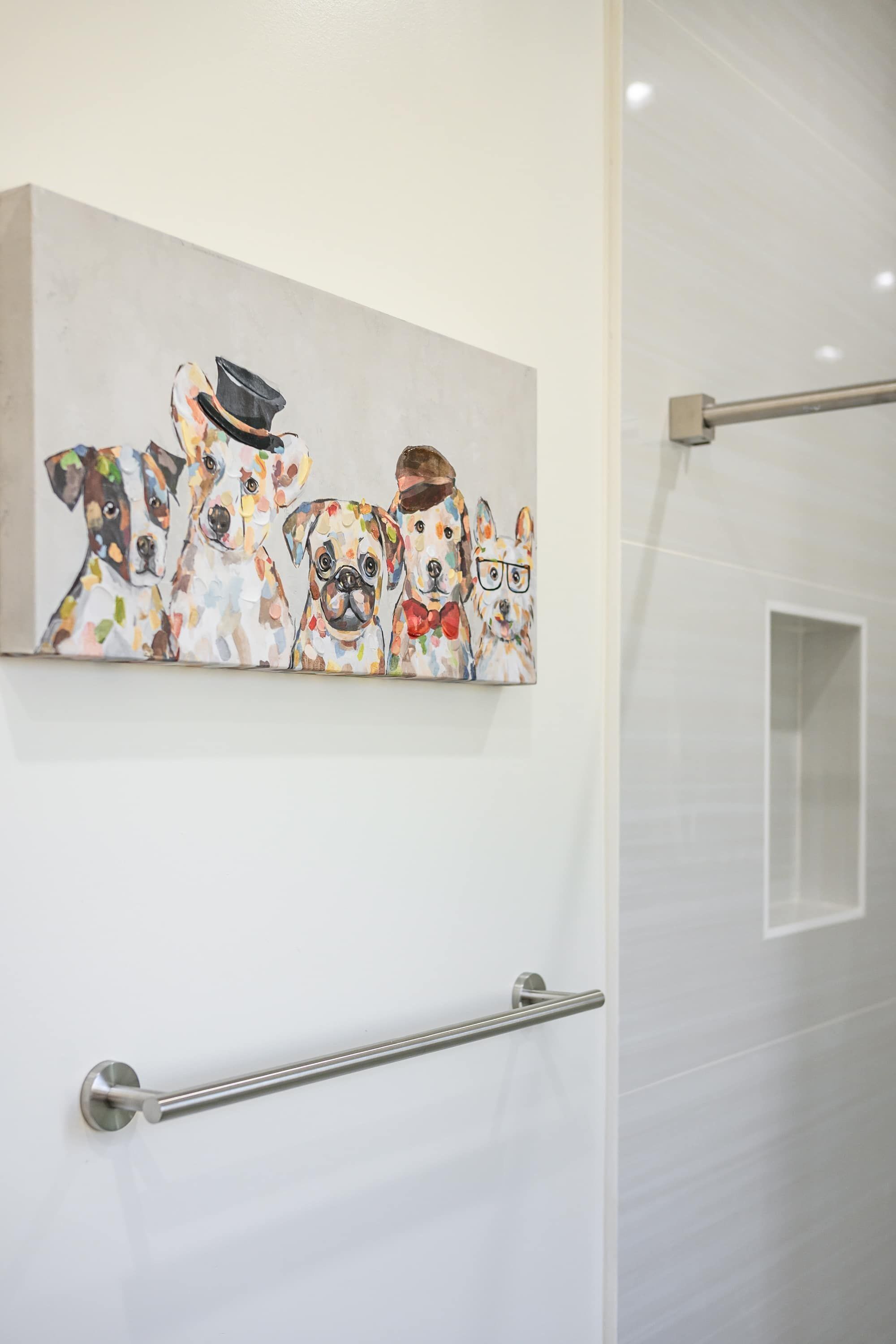 Casa de banho com um quadro de cães na parede, um corrimão e uma porta com puxador.