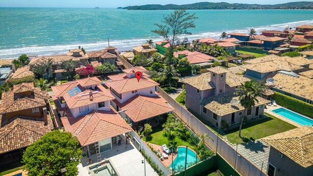 Uma área residencial costeira com casas de telhado vermelho, uma piscina e vista para o oceano.