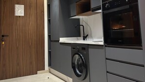 Uma cozinha moderna com eletrodomésticos embutidos, máquina de lavar e porta de madeira.